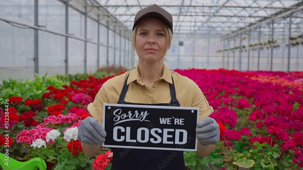 Pretty female flower greenhouse worker showing closed signboard Stock ...