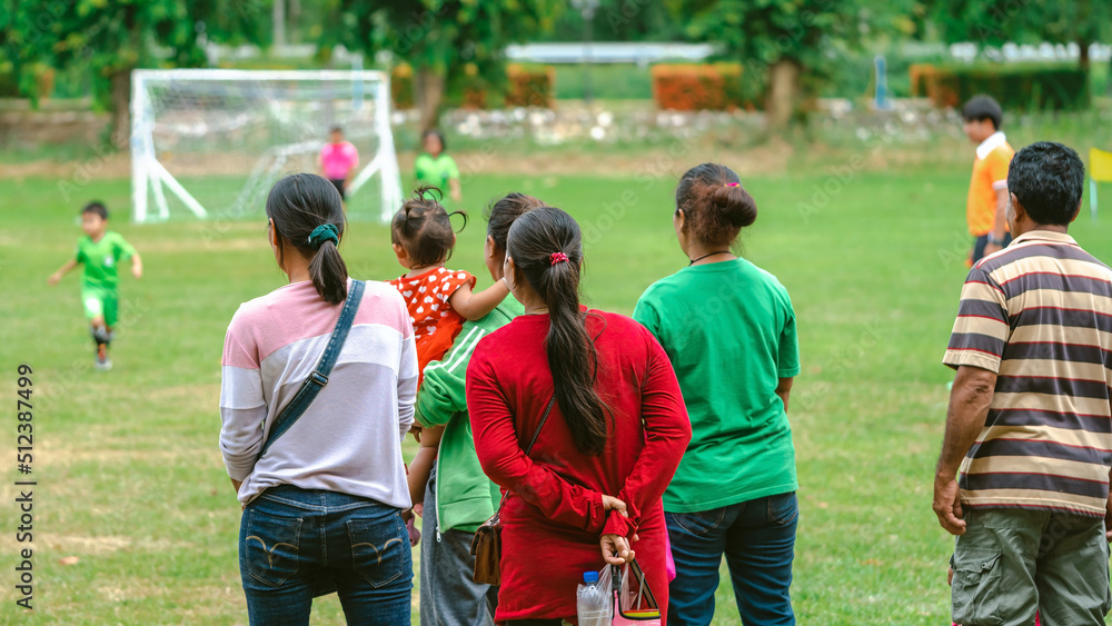 Back view of Moms watch and cheering their sons playing football in ...