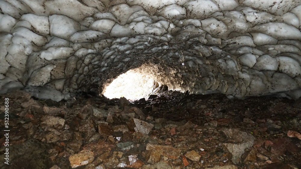 Ice grotto, a snow cave in the mountains in summer. Drops drip from the ...