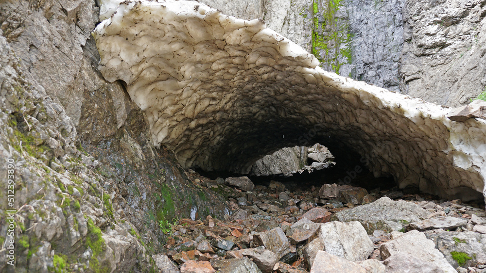 Ice grotto, a snow cave in the mountains in summer. Drops drip from the ...