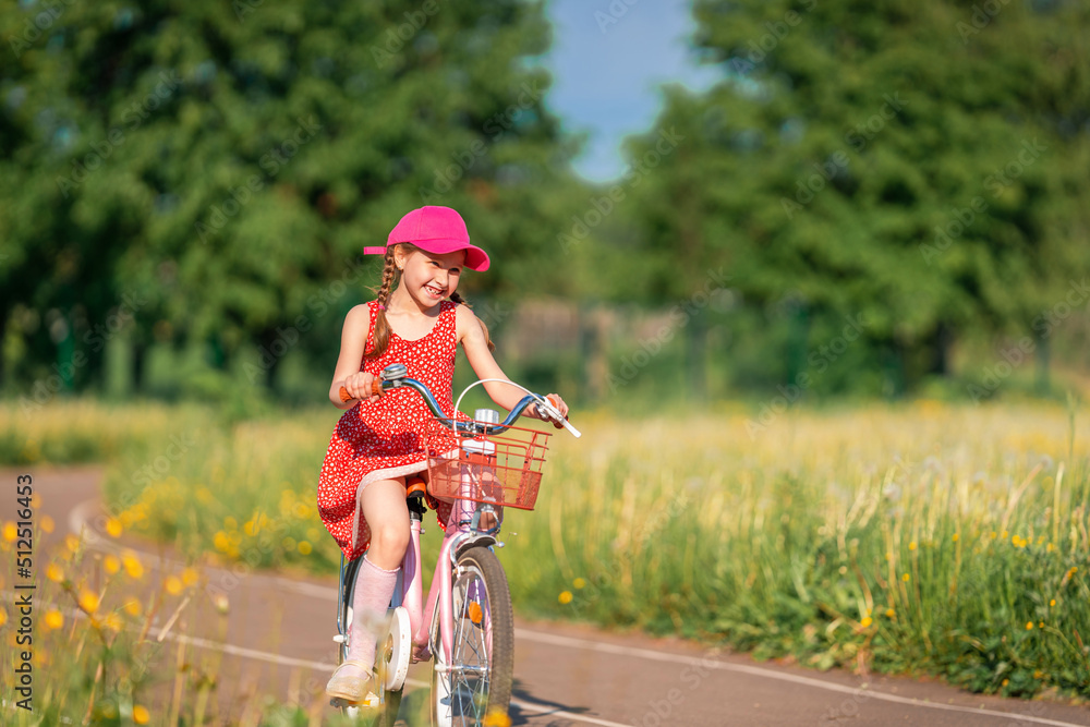 cute little girl rides a bike around the stadium. The child enjoys ...