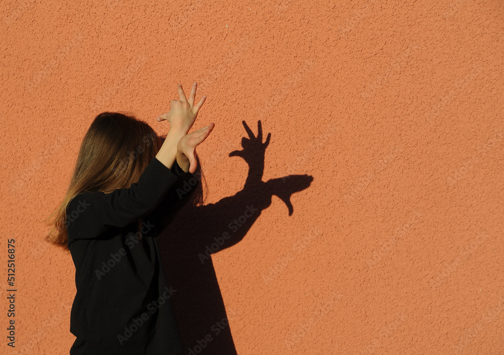 Cute little girl playing in shadow theater on orange color background ...