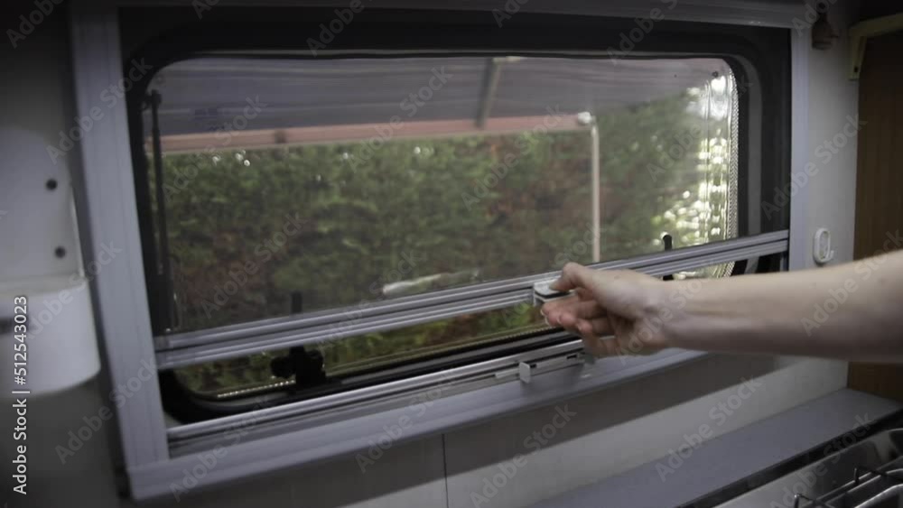Woman closing retractable pleated insect net on a motorhome side window ...