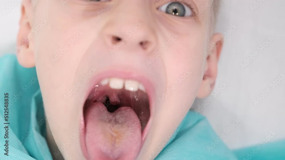 boy opens her mouth wide and pulls out long tongue. child shows his ...