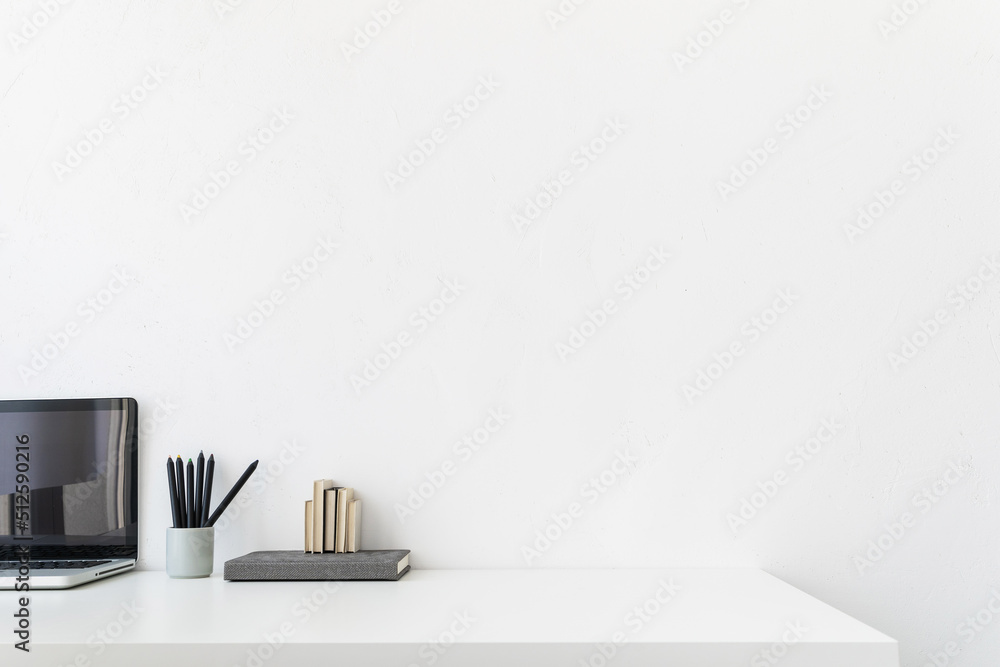 Front view white desk with supplies, mug and white wall copy space ...