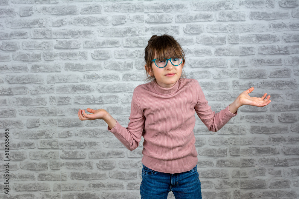 Puzzled and clueless little girl with arms out, shrugging her shoulders ...