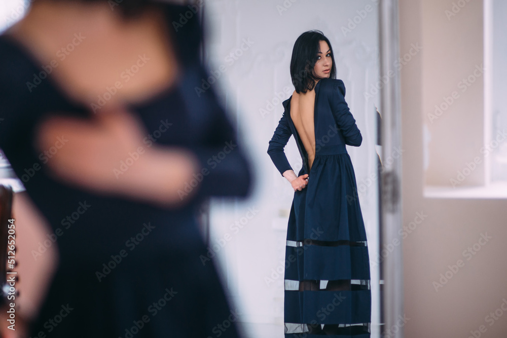 Elegant woman undressing evening dress in front of a mirror in the ...