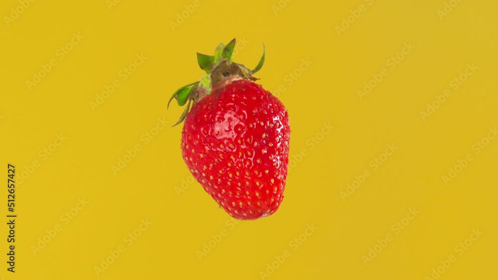 Ripe strawberries on a yellow background rotates. One big fresh red ...