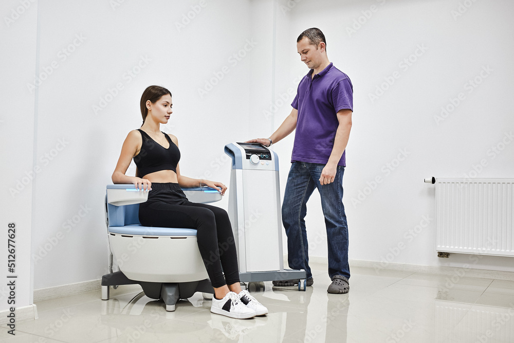 Young woman sitting on electromagnetic chair for stimulation of deep ...