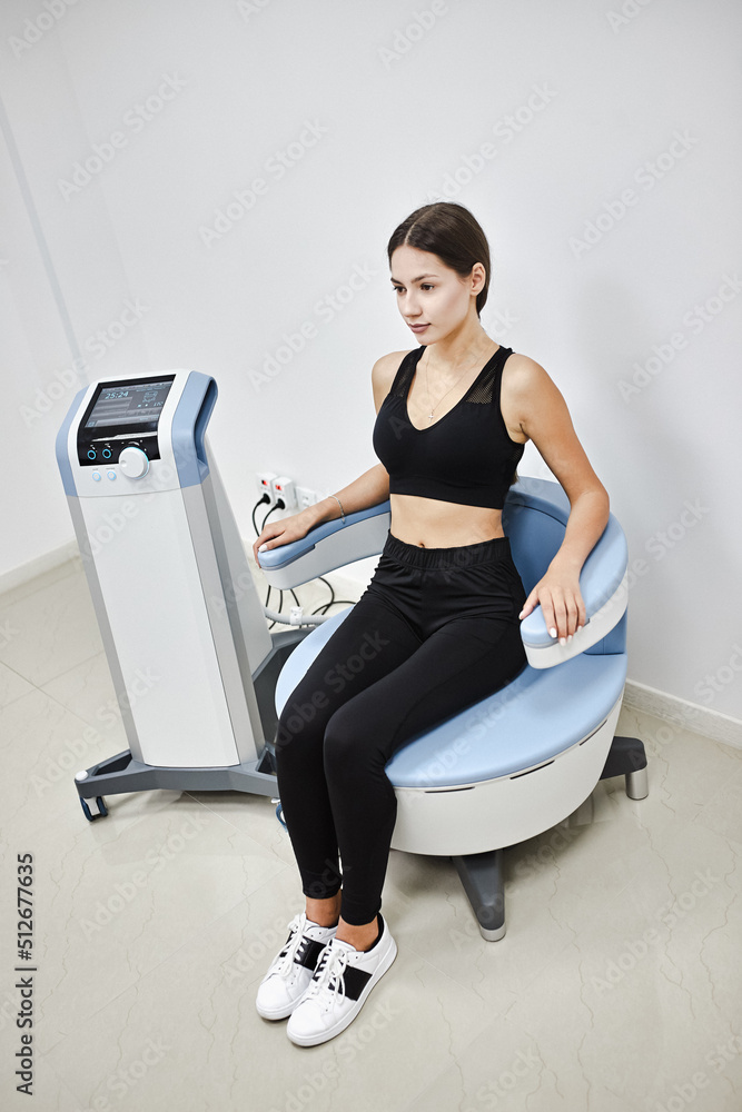 Young woman sitting on electromagnetic chair for stimulation of deep ...