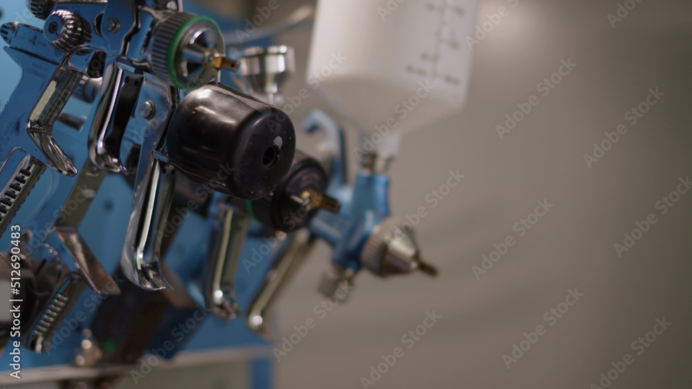 Close up rack focus four spray guns in cabinet. High-precision ...