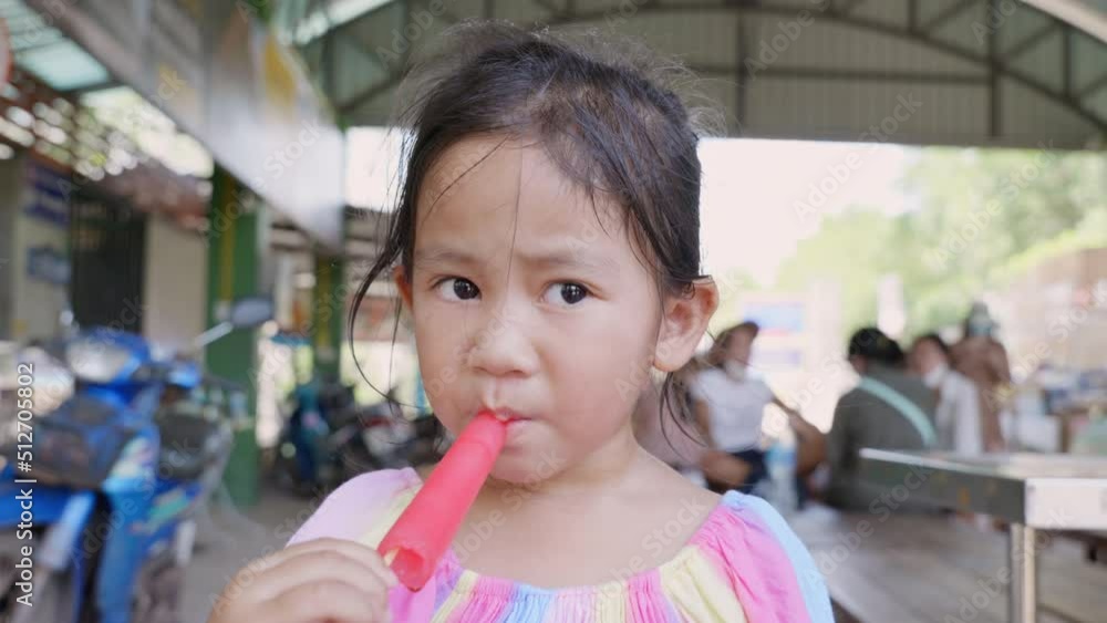 Vidéo Stock Happy Asian little girl eating popsicle at summertime ...