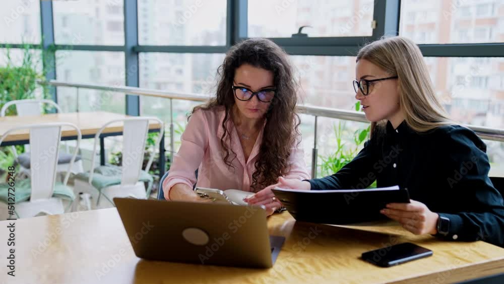 Young female colleagues talking about working issues sitting at the ...