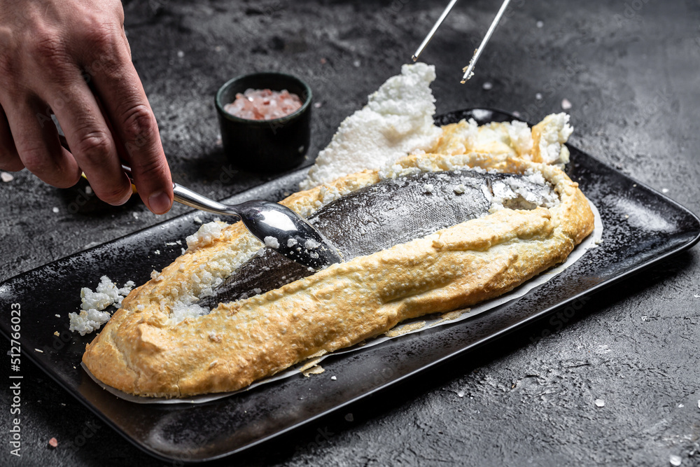 Fish covered in meringue salt. Tray with fish and lemon. Breaded river ...