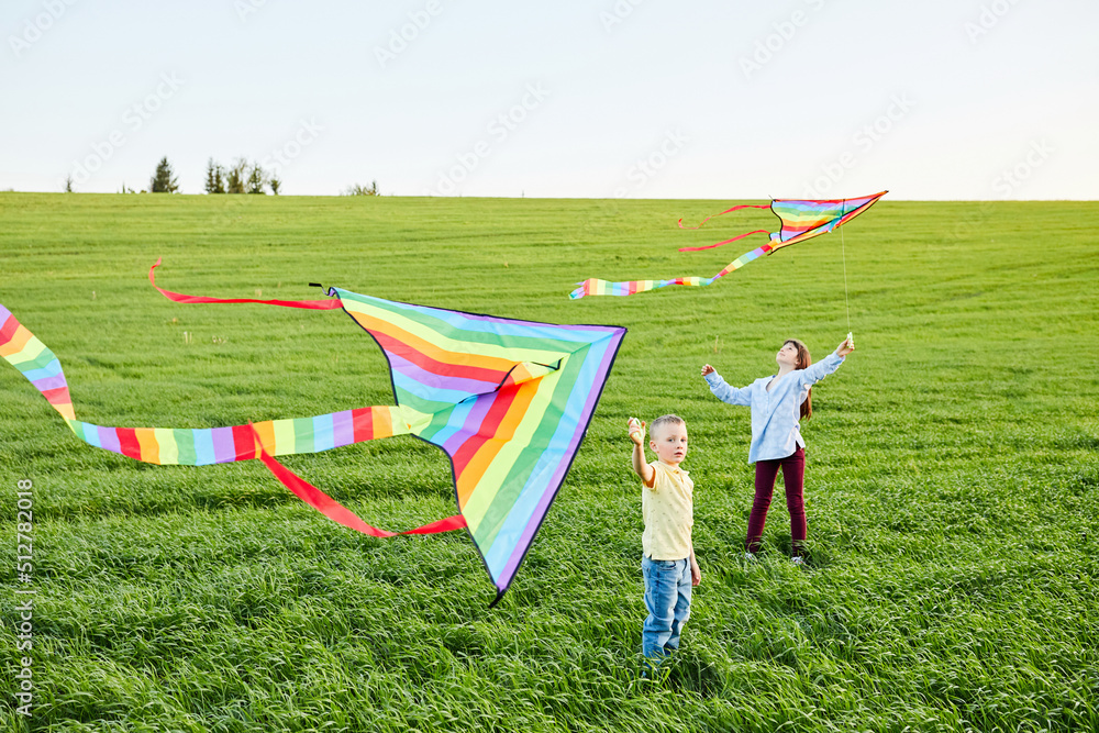 Smiling girl and brother boy running with flying colorful kites on the ...