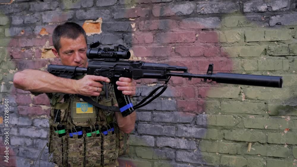 The Ukrainian soldier takes aim with his assault rifle with silencer on ...