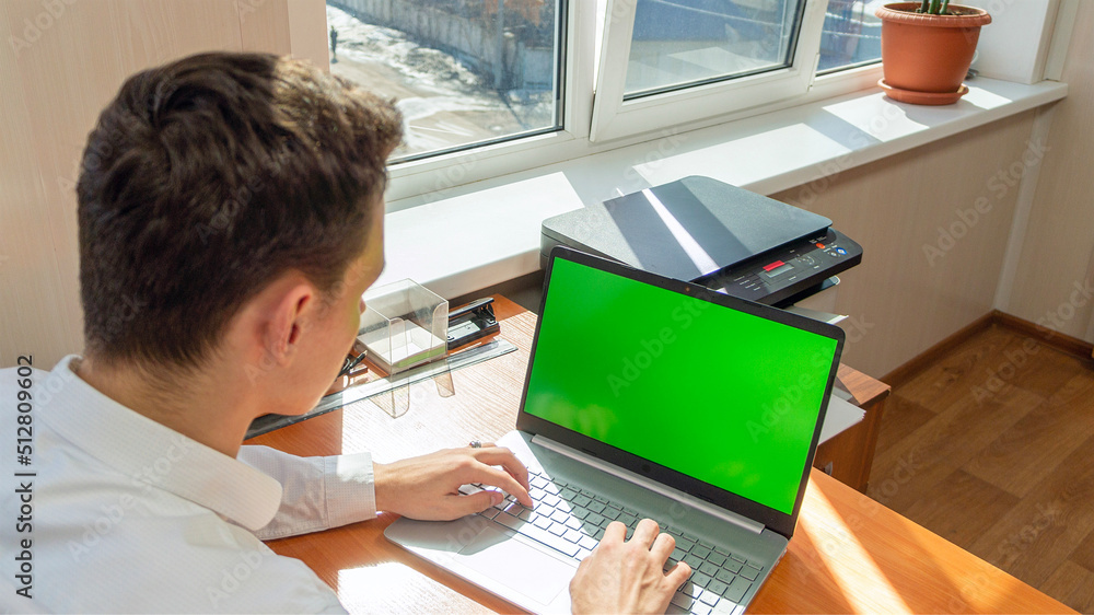 Rear view of a businessman using a laptop to type in the office. The ...