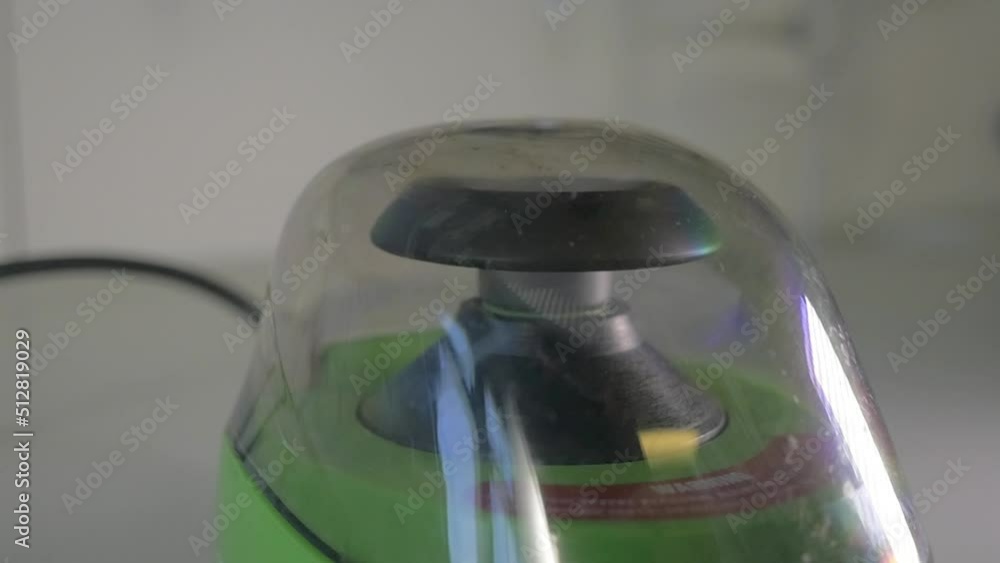 Centrifuge vortex mixer spinning vials with blue liquid. Close up ...