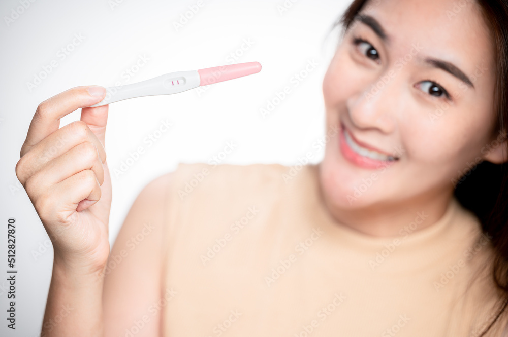 Asian woman holding pregnancy test feeling happy by positive result ...