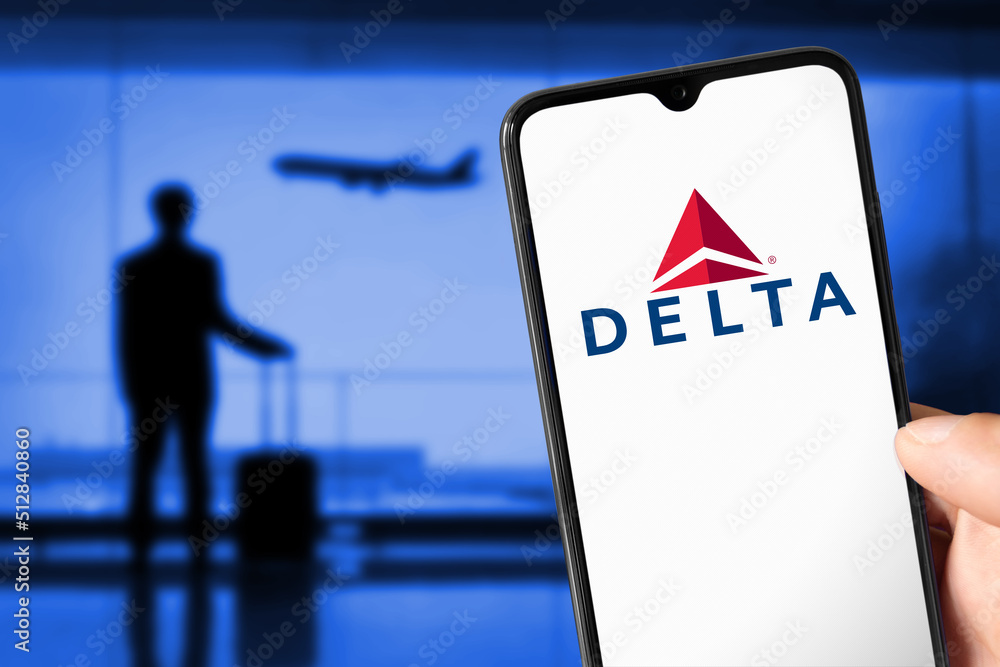 Delta Airlines logo on smarthphone screen with man looking aircraft in ...