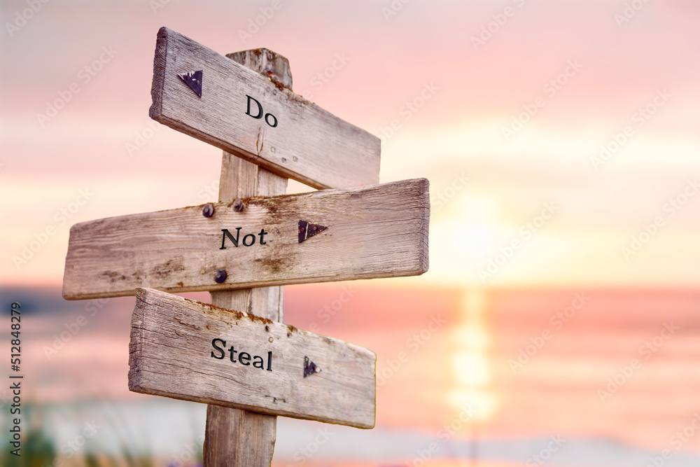 do not steal text quote on wooden crossroad signpost outdoors on beach ...