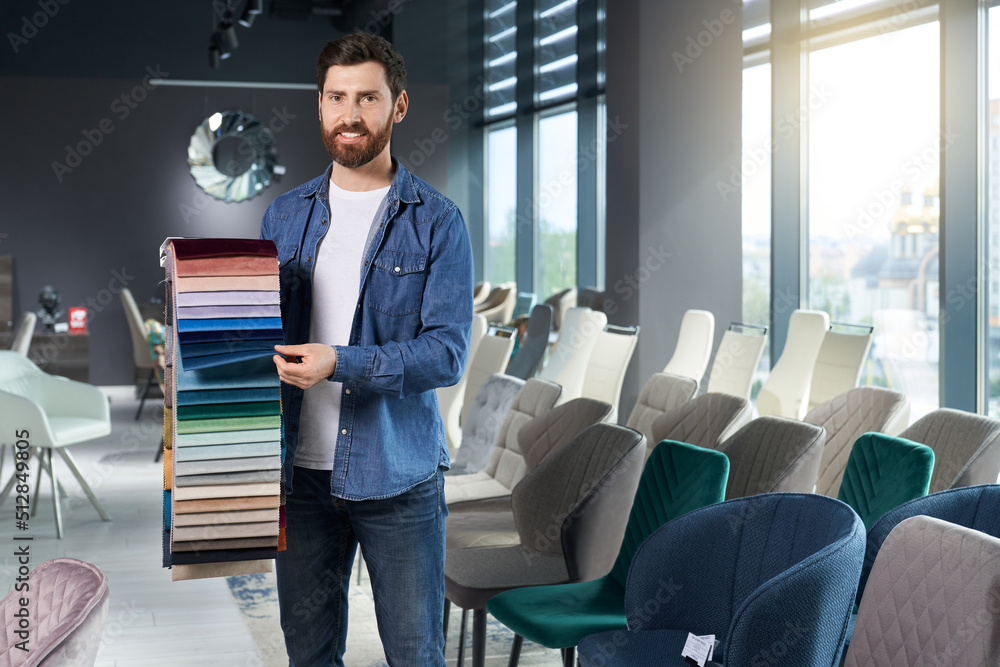 Professional male decorator presenting various samples of upholstery ...