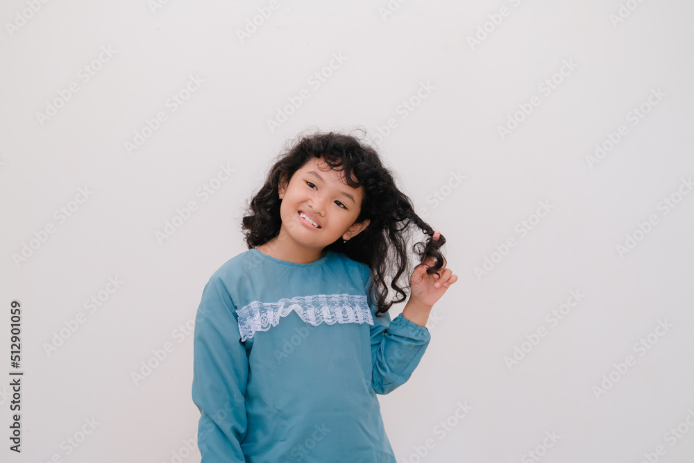 Cute smiling Asian little girl playing with her curly hair, isolated on ...