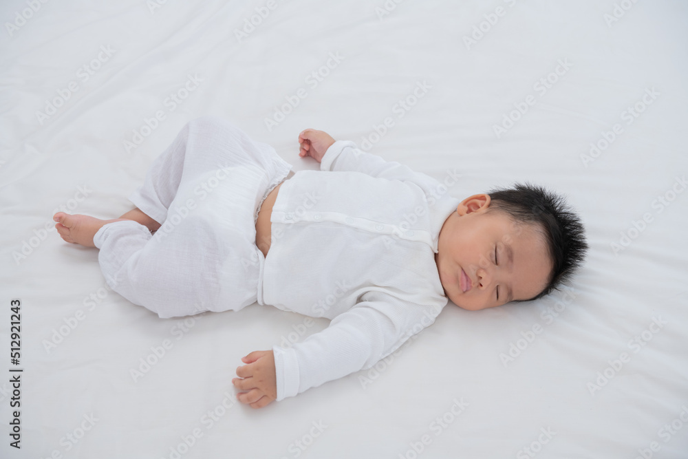 Baby sleeping in bed. Baby boy wearing diaper in white sunny bedroom ...
