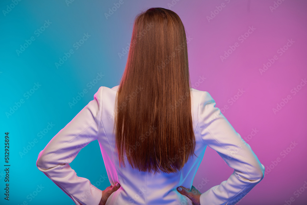 Woman with long hair standing back with hands on hip, portrait with ...