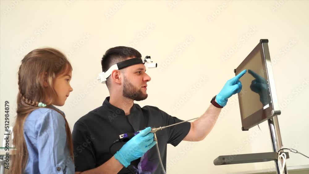 ENT doctor otolaryngologist with headlight showing to child endoscope ...