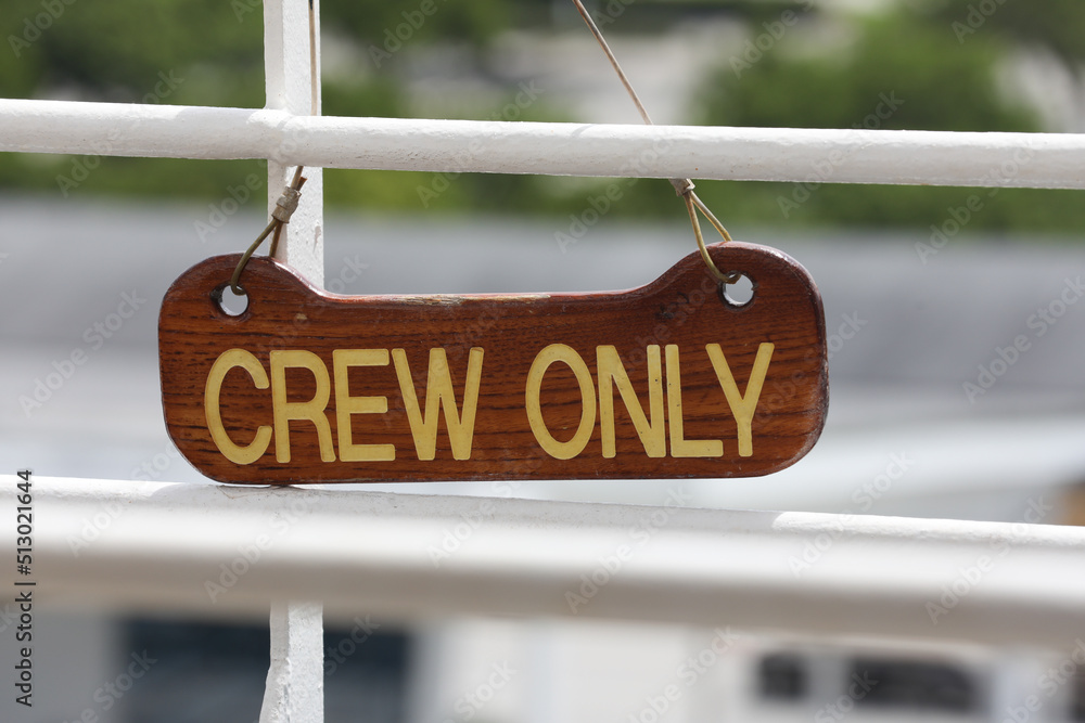 Crew only sign on a ship against a blurred background with ropes and a ...