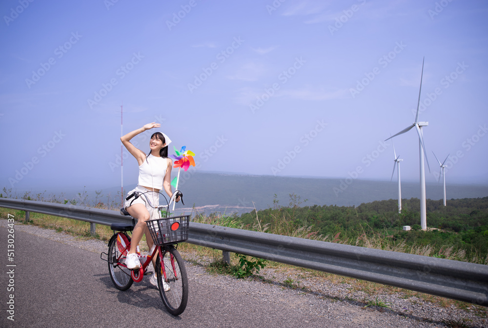 woman on vintage bicycle with on the background huge windmill turbines ...