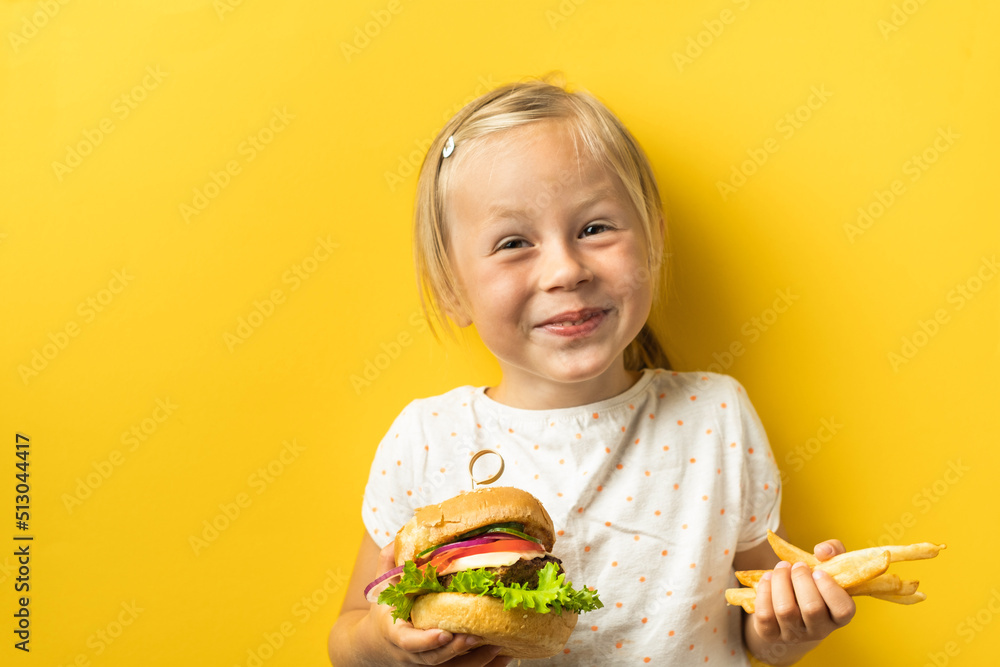 Cute little caucasian girl with blonde hair enjoying burger on a yellow ...