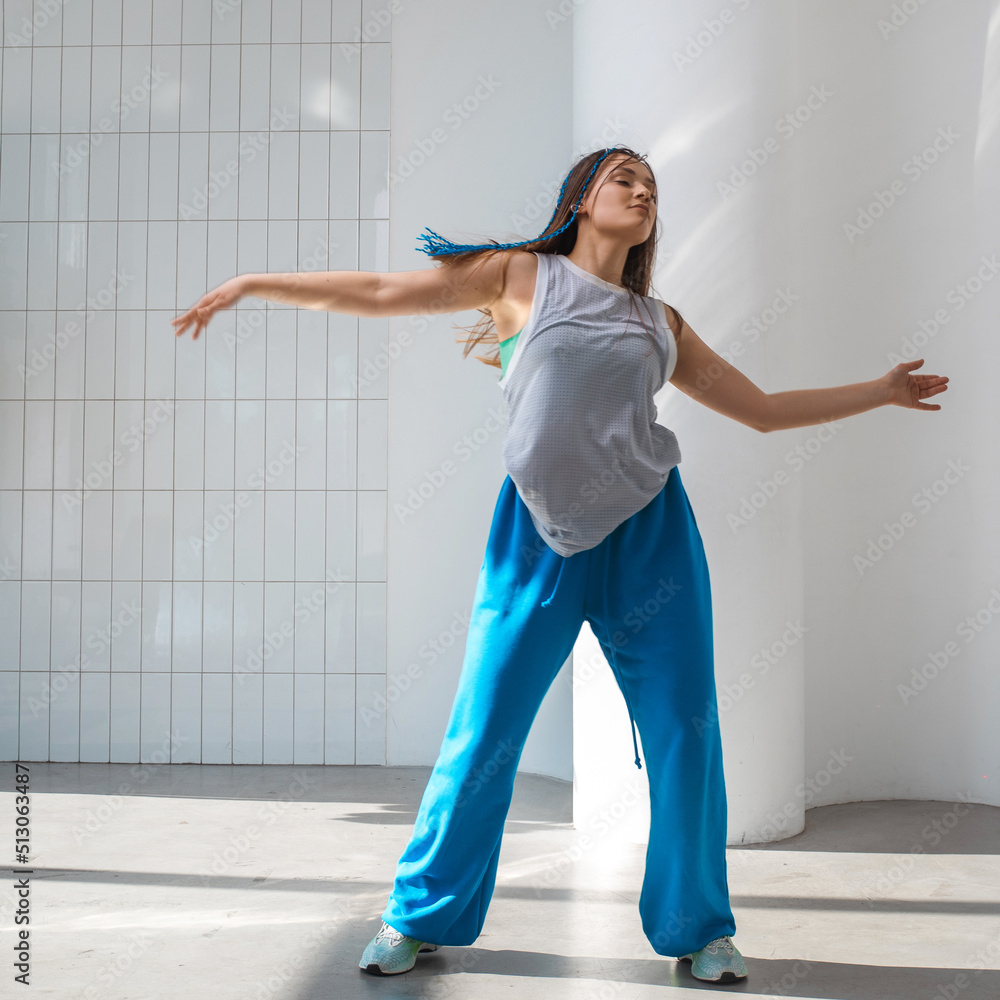 Modern dance, stylish young brunette in baggy blue pants dancing in ...