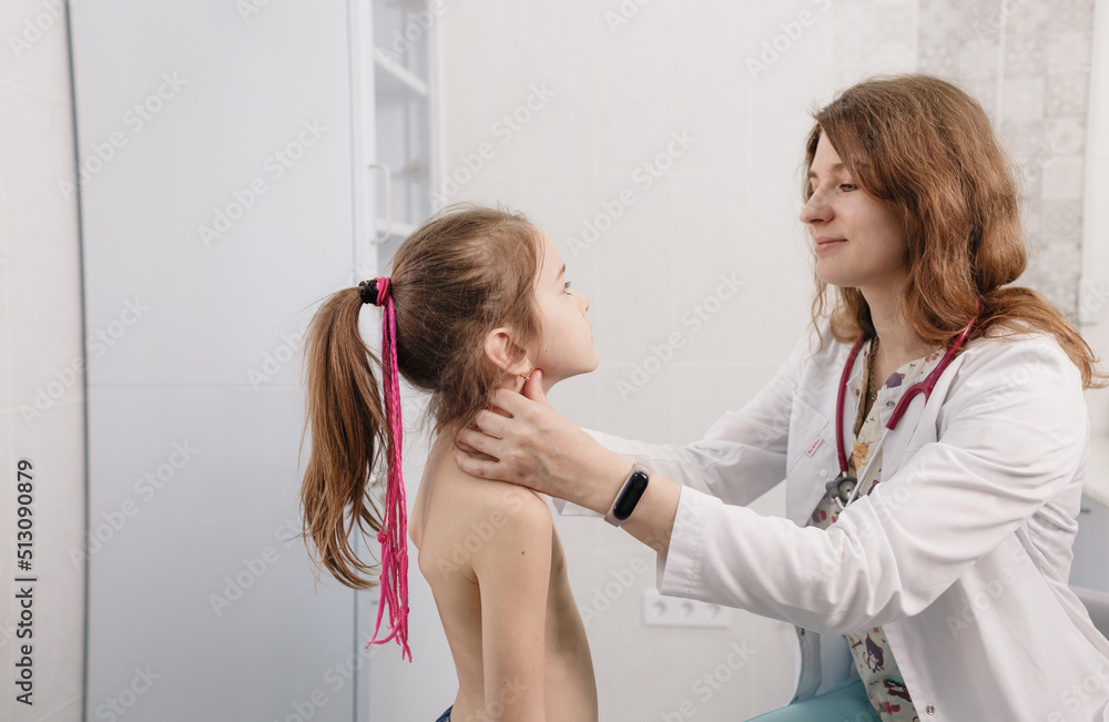 A pediatrician carefully examines a little girl in the office and ...