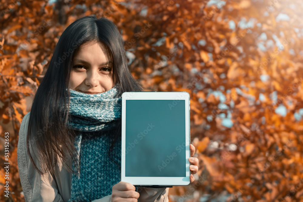 Girl shows the screen of the tablet to the viewer while standing ...