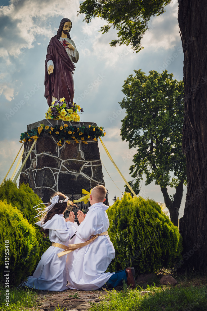 Children pray to god. The children are kneeling on the statue of Jesus ...
