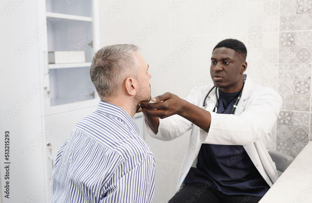 an African-American doctor examines the patient examines the lymph ...