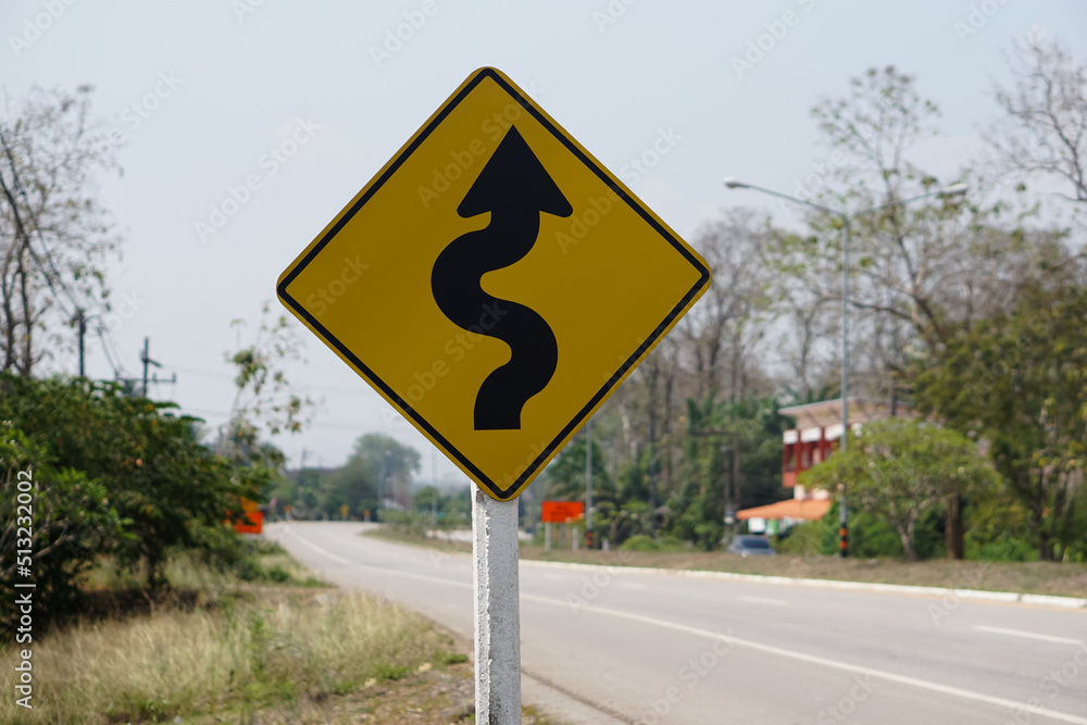 Yellow traffic sign with twisty arrow symbol at rural road Thailand to ...