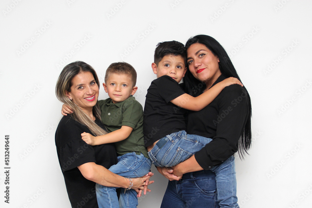 Two moms and two male sons young children pose for family portrait very ...