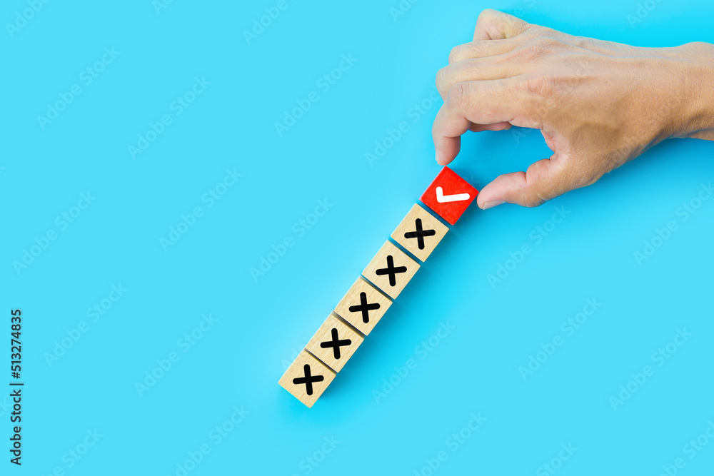 Hand choose check mark on cube wooden toy block with cross symbol for ...