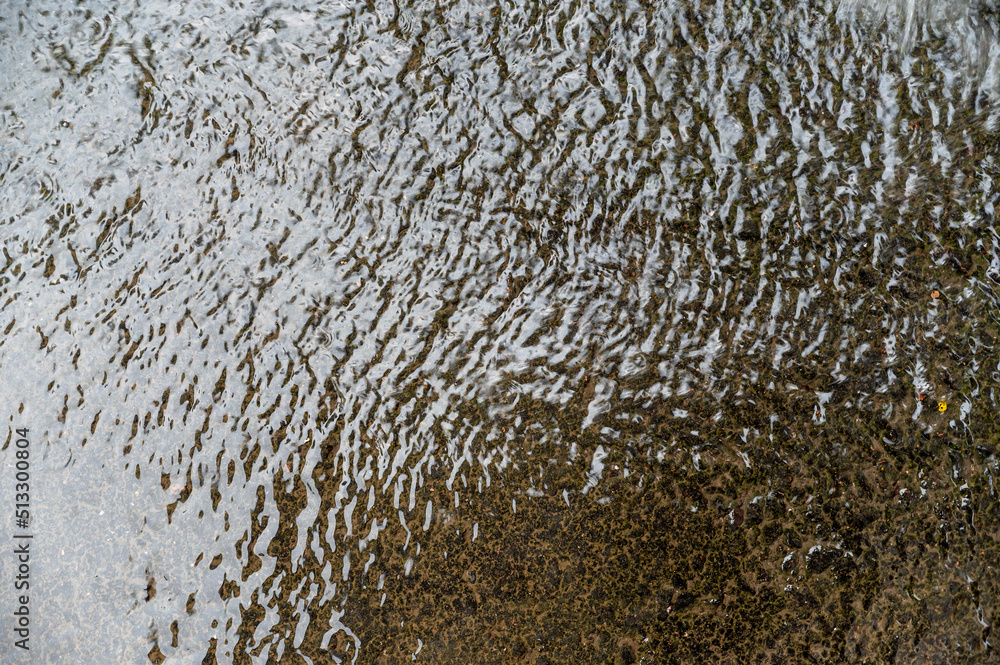 Texture of rain stream on city street. Transparent rainwater flowing on ...