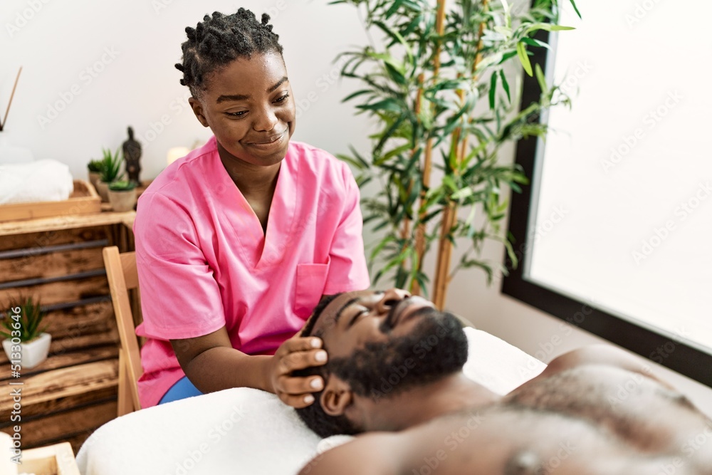 Young physiotherapist woman giving head massage to african american man ...
