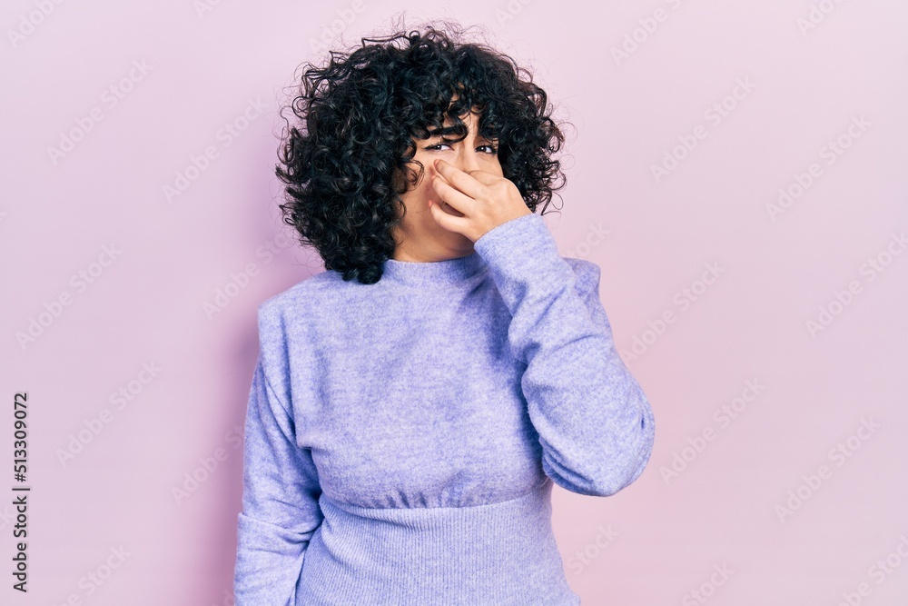 Young middle east woman wearing casual clothes smelling something ...