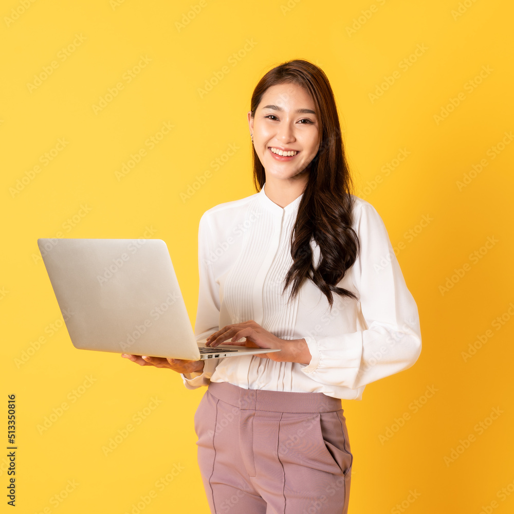 Young attractive woman in smart casual cloth using laptop on yellow ...