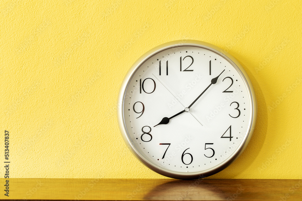 A clock on wooden table with yellow wall background, 8 o'clock 7 ...