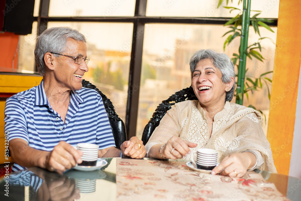 Happy indian senior couple sitting in living room with cup of tea or ...