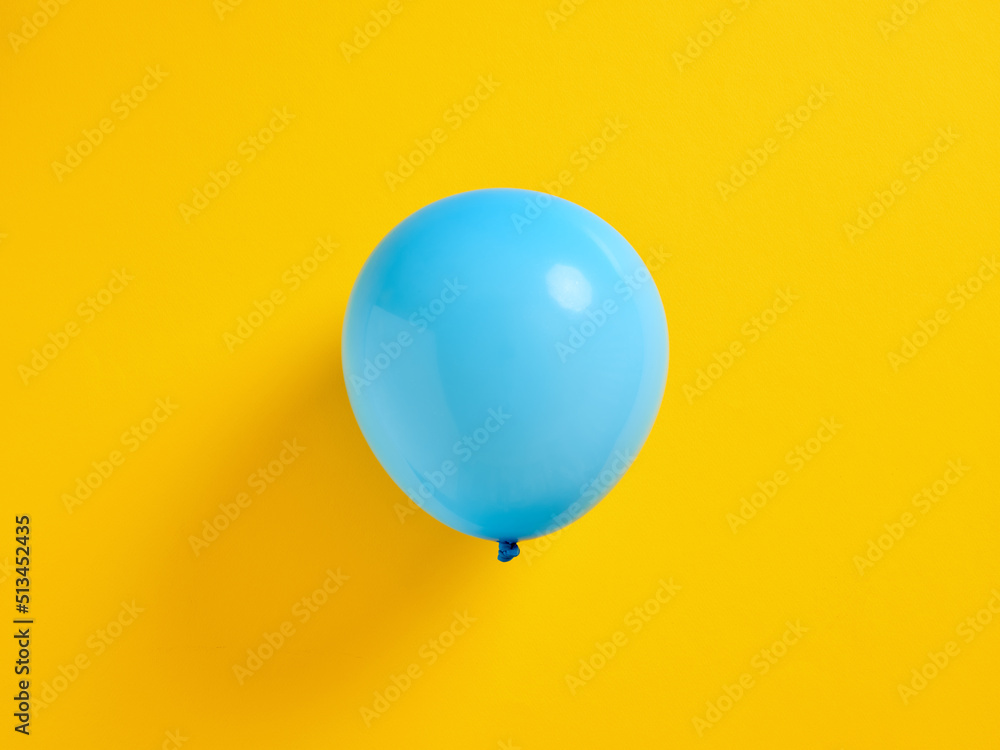 Blue inflated balloon on yellow background. Stock Photo | Adobe Stock