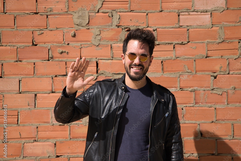Young Latino man, dark with beard and sculpted body greets with raised ...