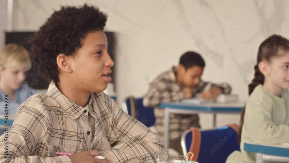 Chest up slowmo of African American middle school girl raising hand and ...